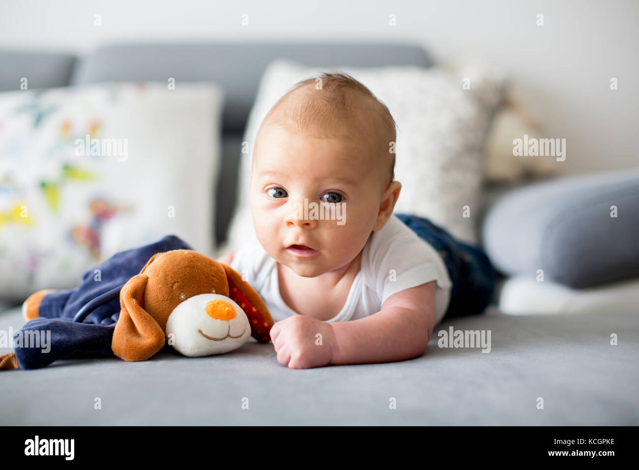 Adorable little baby boy, playing with toy, looking curiously at camera ...