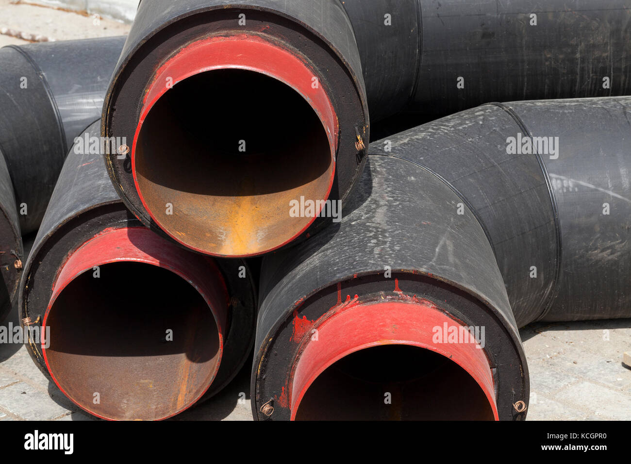 Large diameter wide metal pipes covered with a thick layer of black ...