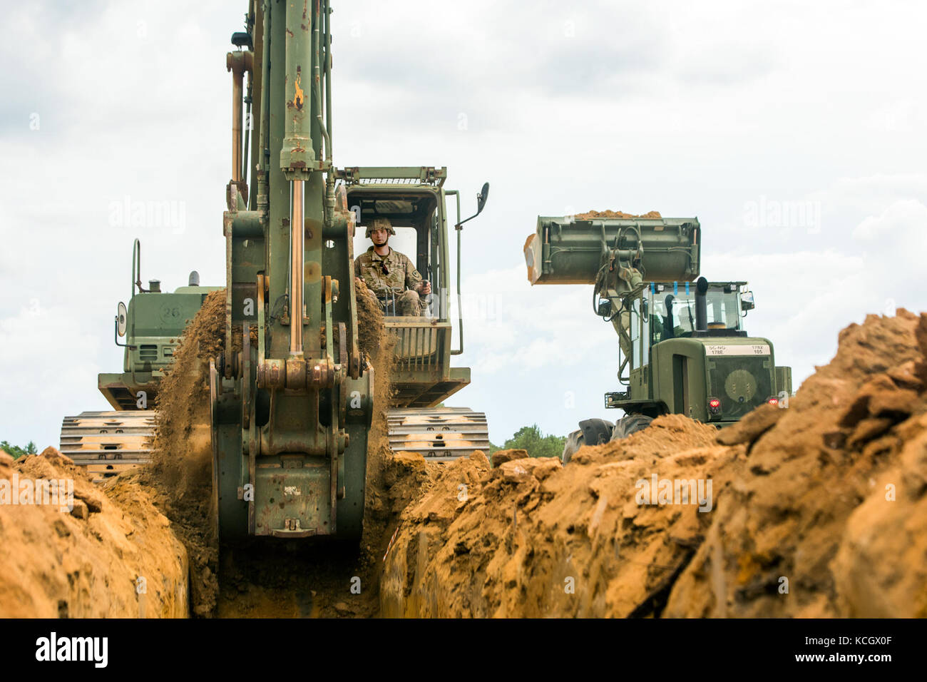 U.S. Army Sgt. Jim Miller operates a heavy equipment excavator to dig a ...