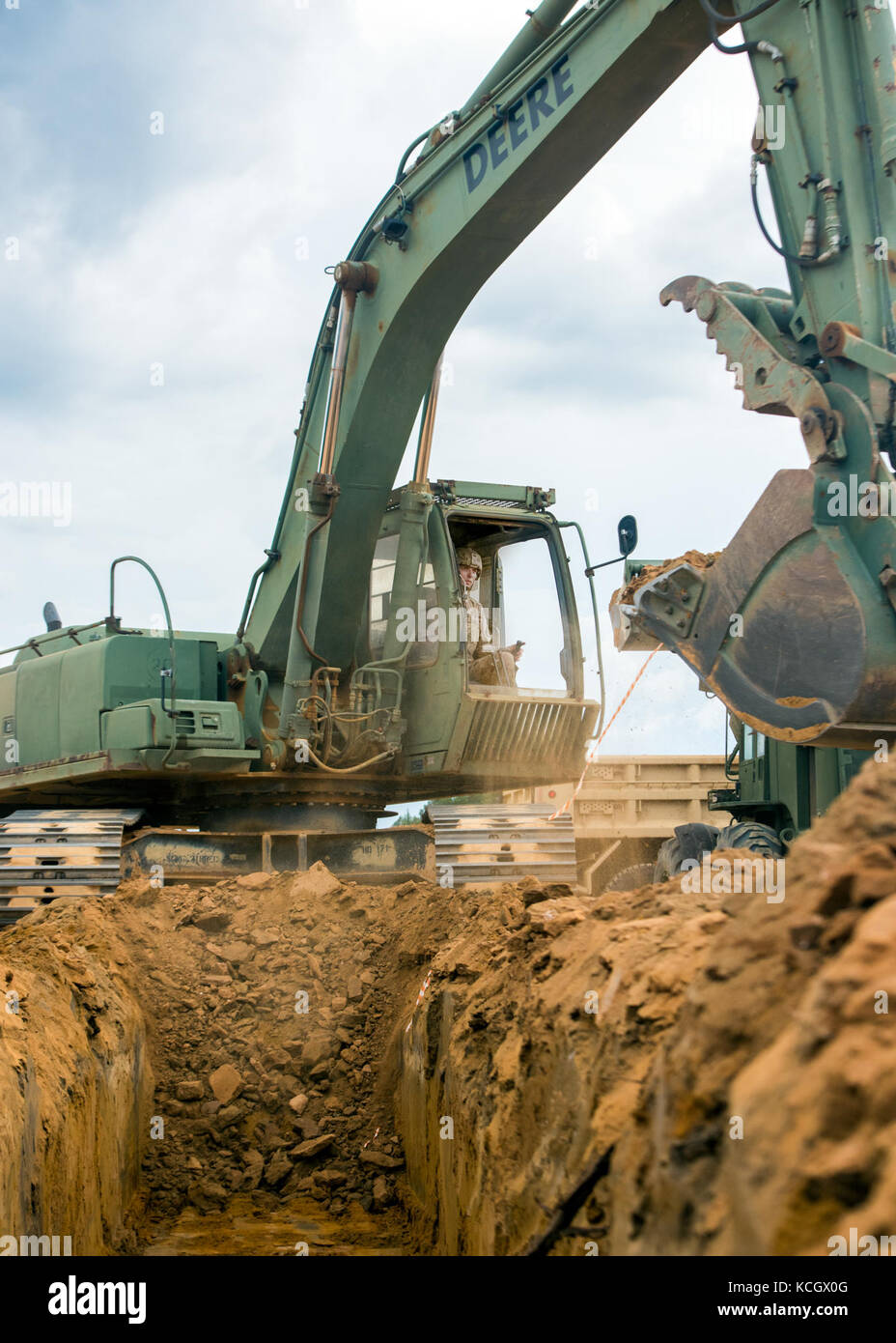 U.S. Army Sgt. Jim Miller operates a heavy equipment excavator to dig a ...