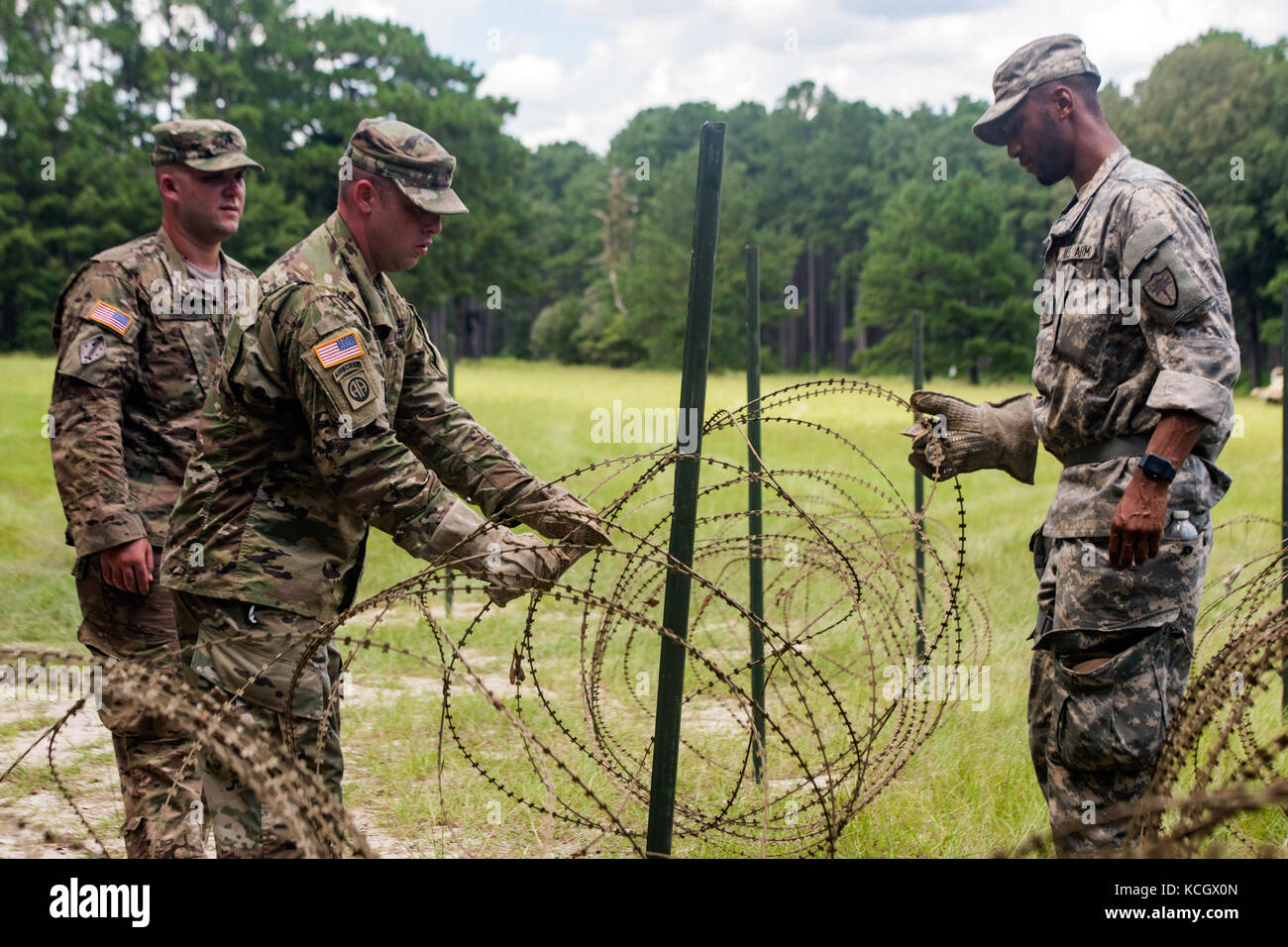 Soldiers construct a protective barrier using concertina wire during ...