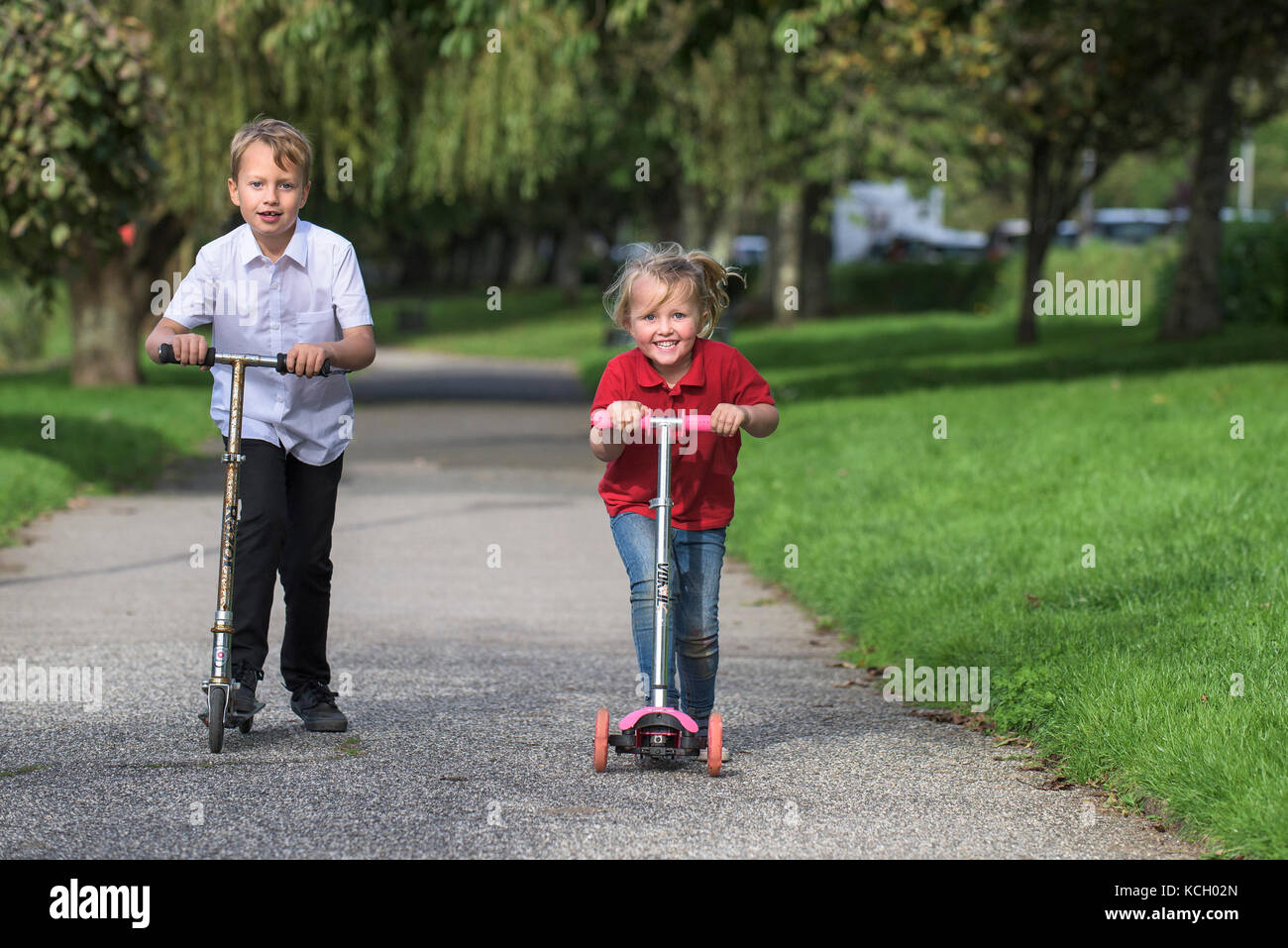 Children riding their scooters - a young boy and his young sister ...