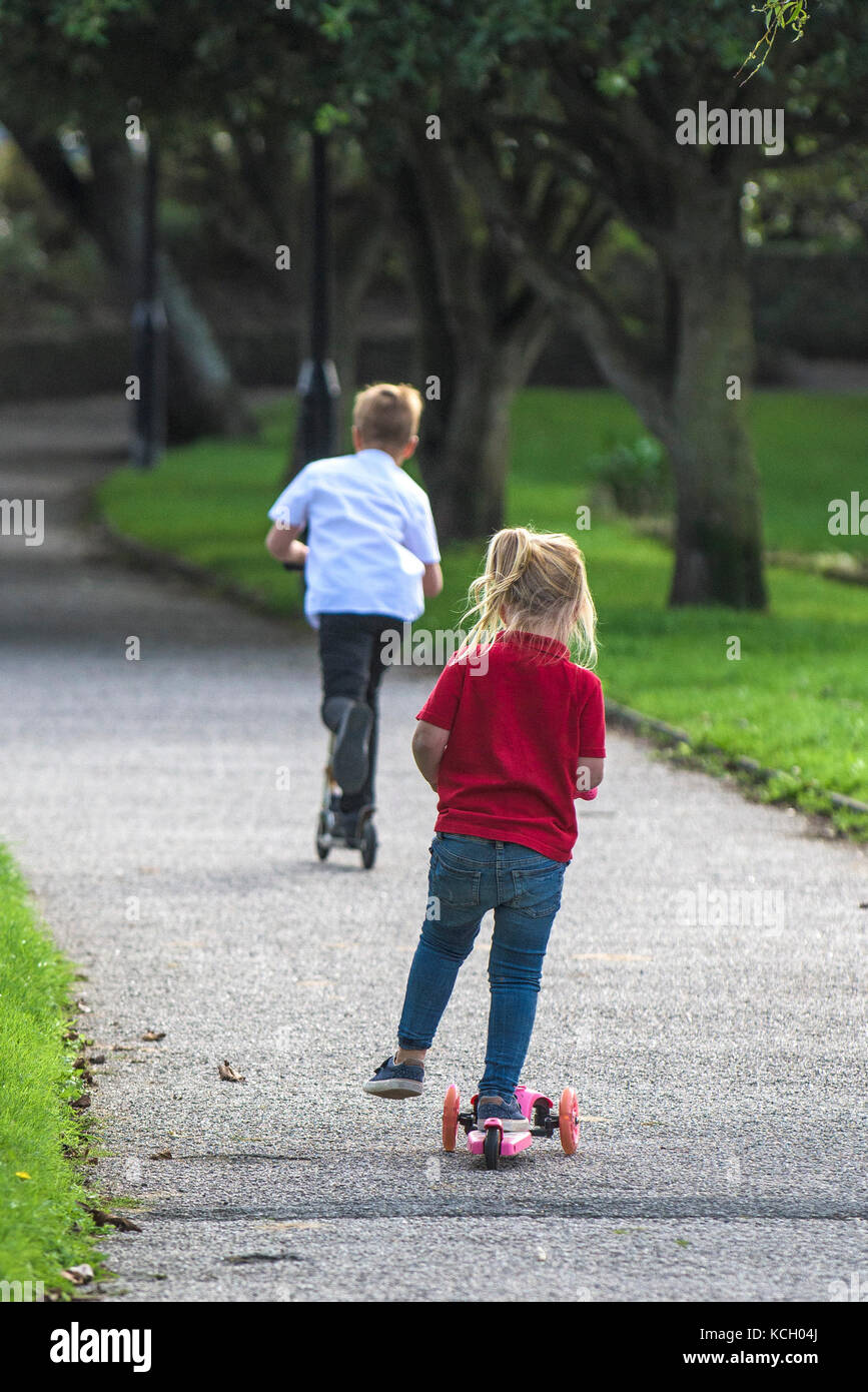 Children riding scooters - two children having fun riding scooters ...