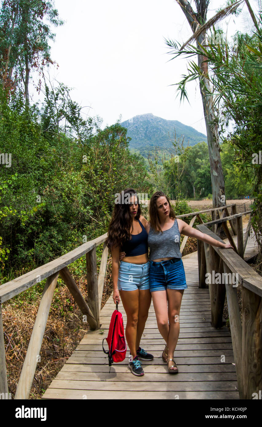 Two beautiful women hiking in nature on a wooden path in the mountains ...