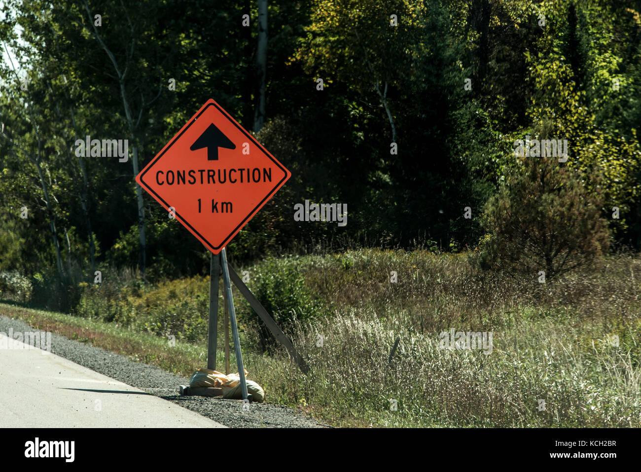 Orange construction worker sign at a road into the distance on trans ...