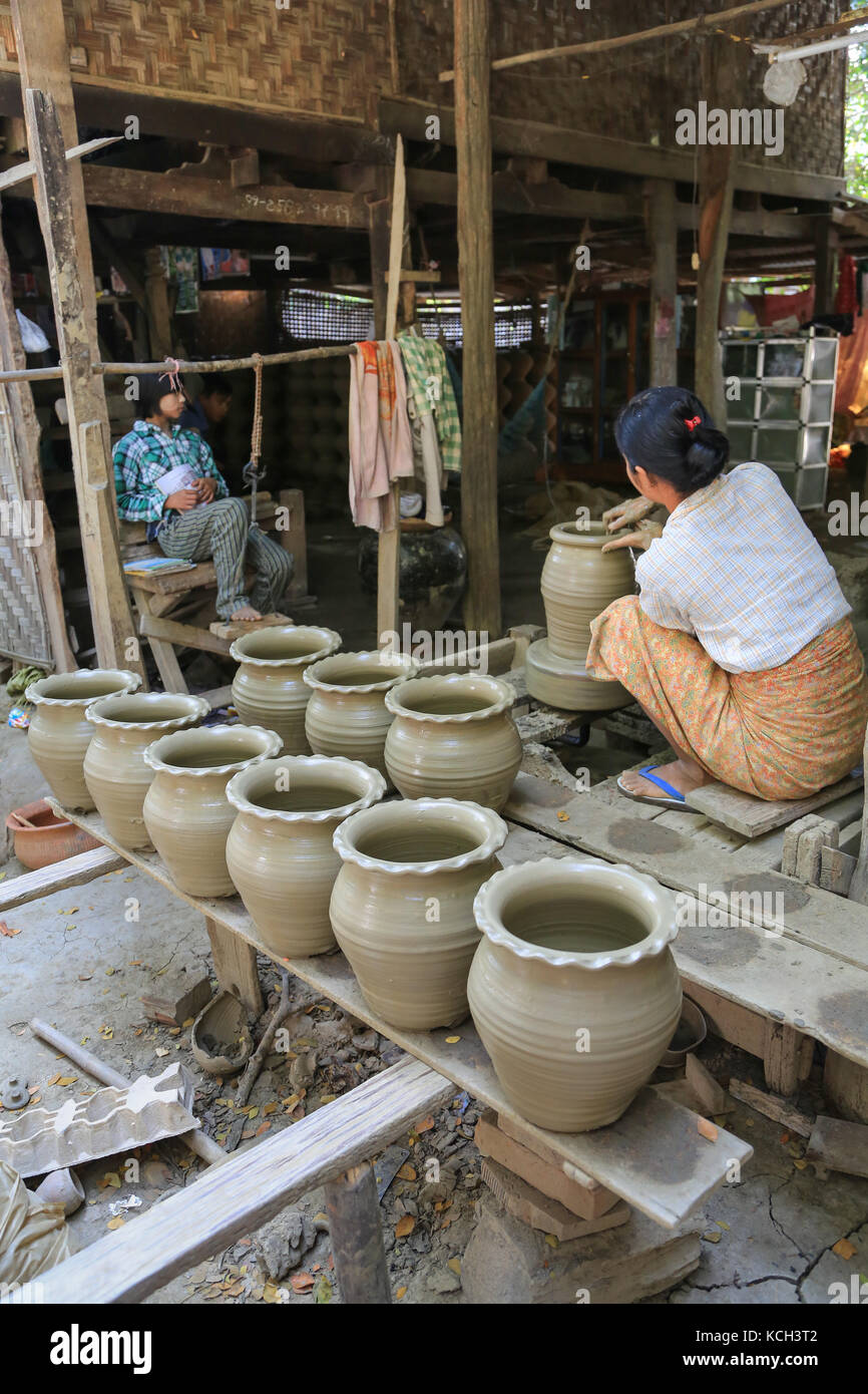 A woman is forming a pot on a pottery wheel in Yandabo Village on the ...