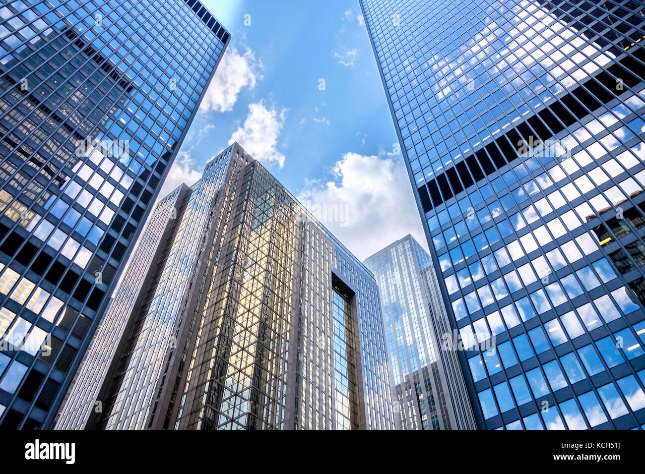 Blue sky and clouds reflect in the windows of downtown office building ...