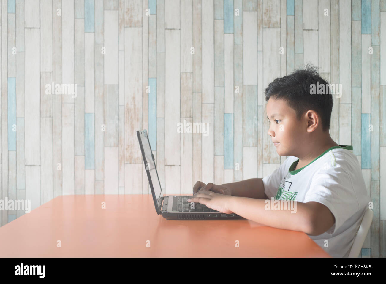 young asian boy using laptop computer at dining table at home ...