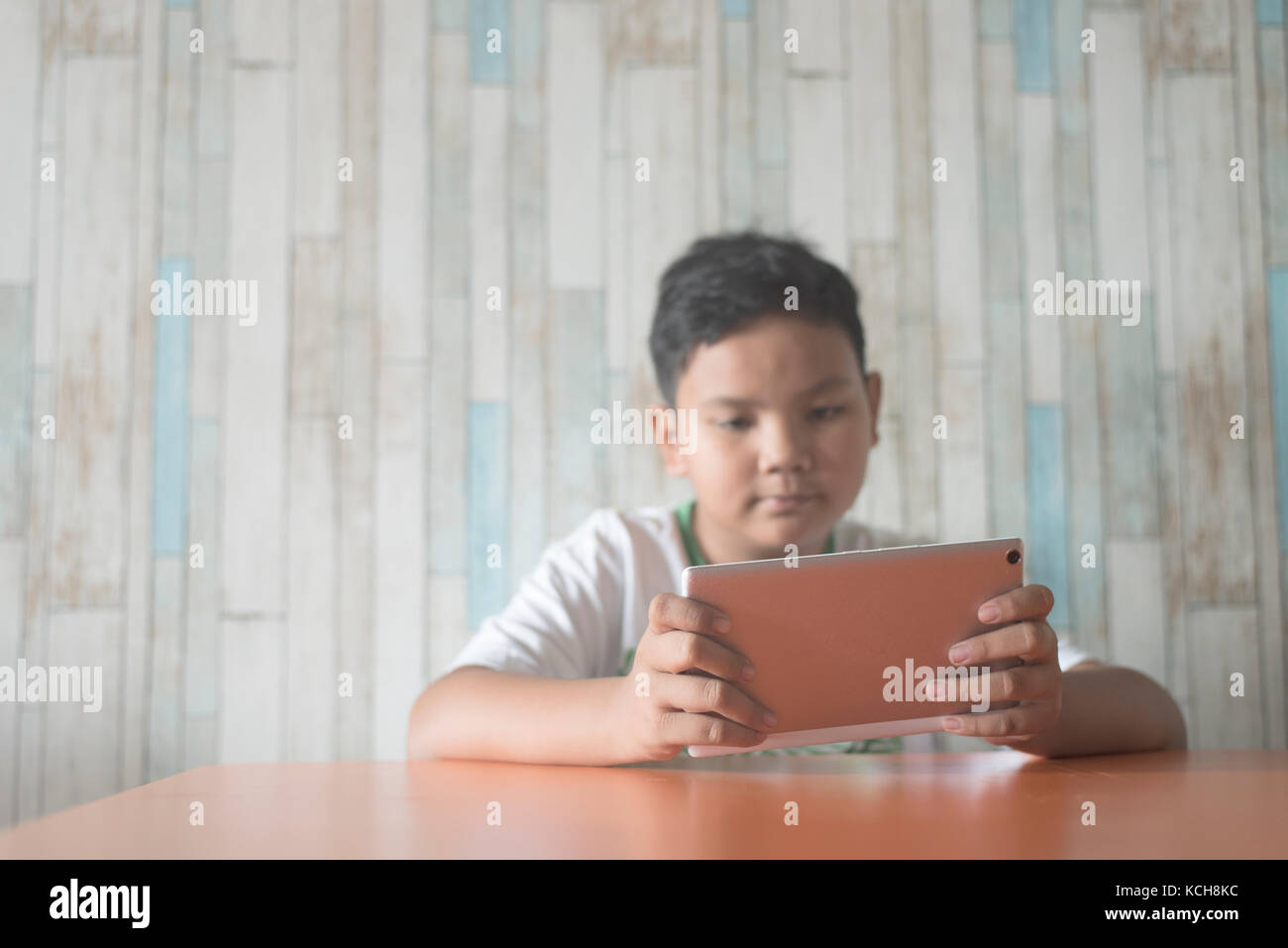young asian boy using digital tablet at the dining table at home (focus ...