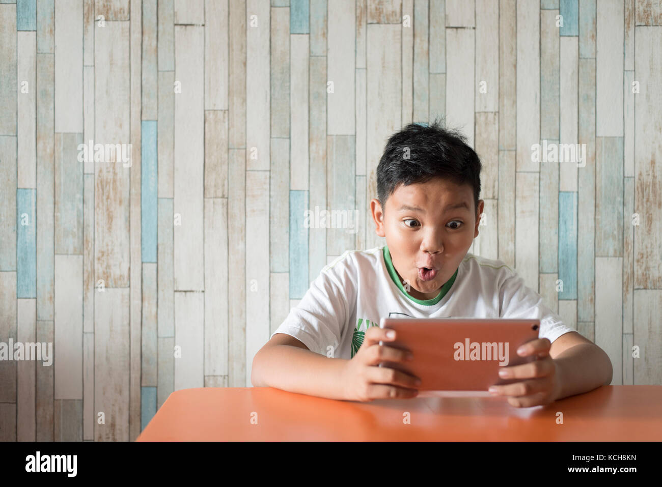 young asian boy using digital tablet at the dining table at home with ...