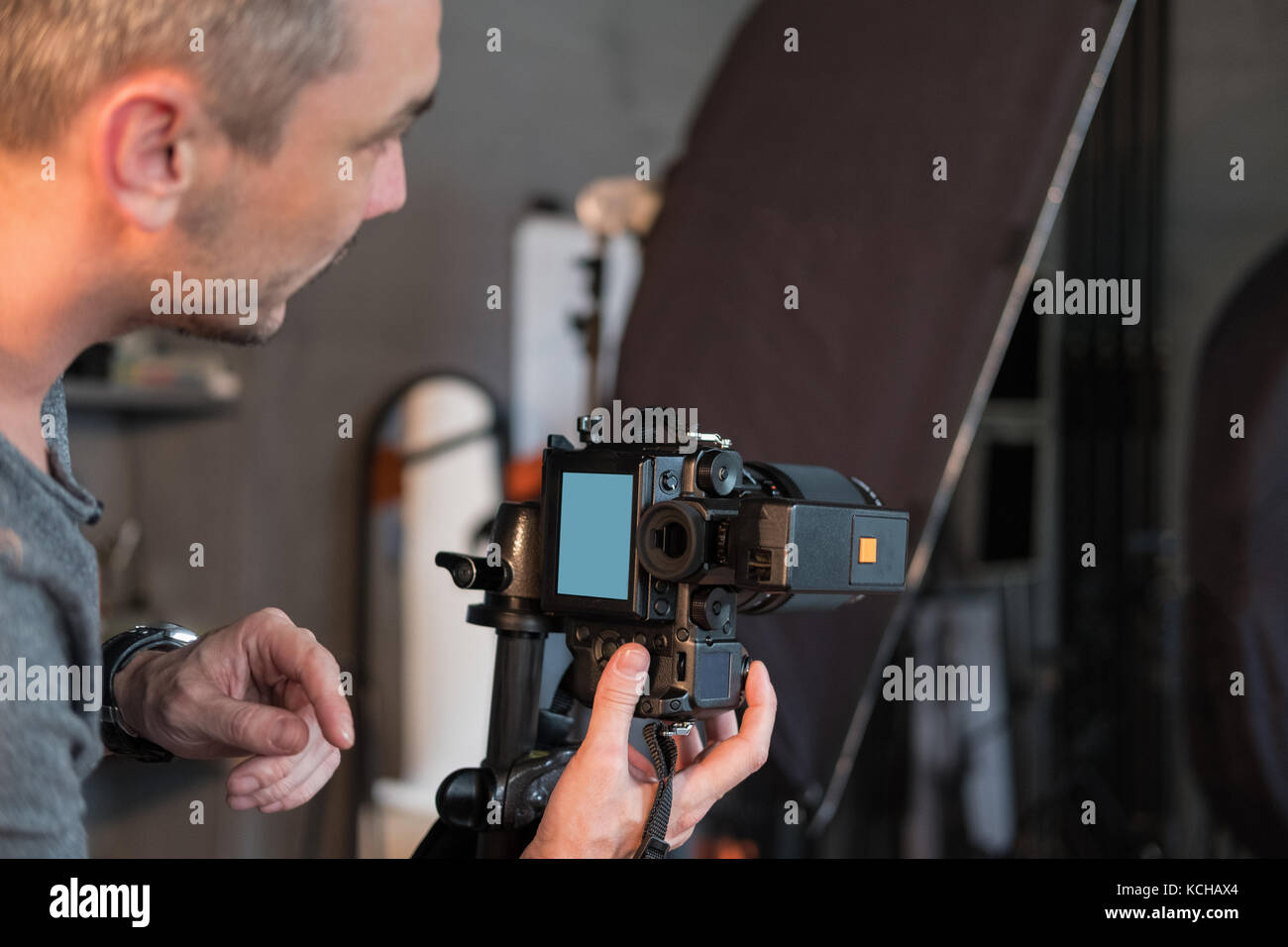 a young photographer in the process of shooting in Studio, side view ...