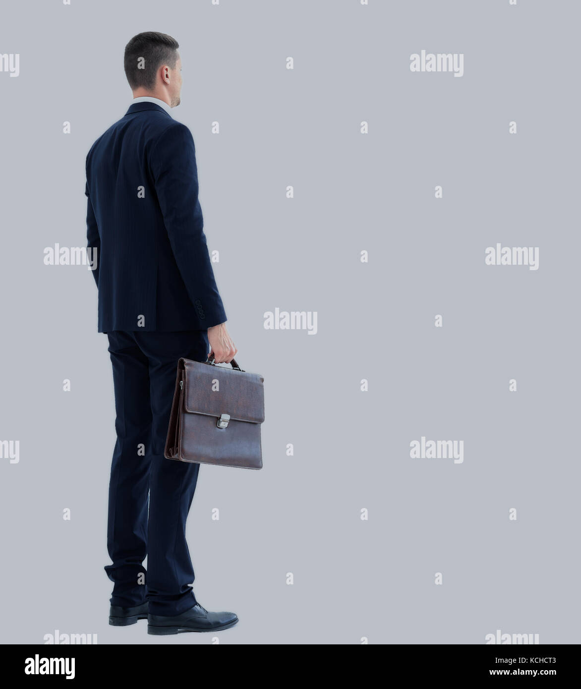 Young sales businessman in elegant suit standing with his back in empty ...