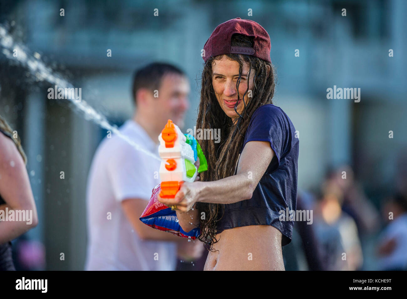 A woman with dreadlocks fires a water pistol during a charity water ...