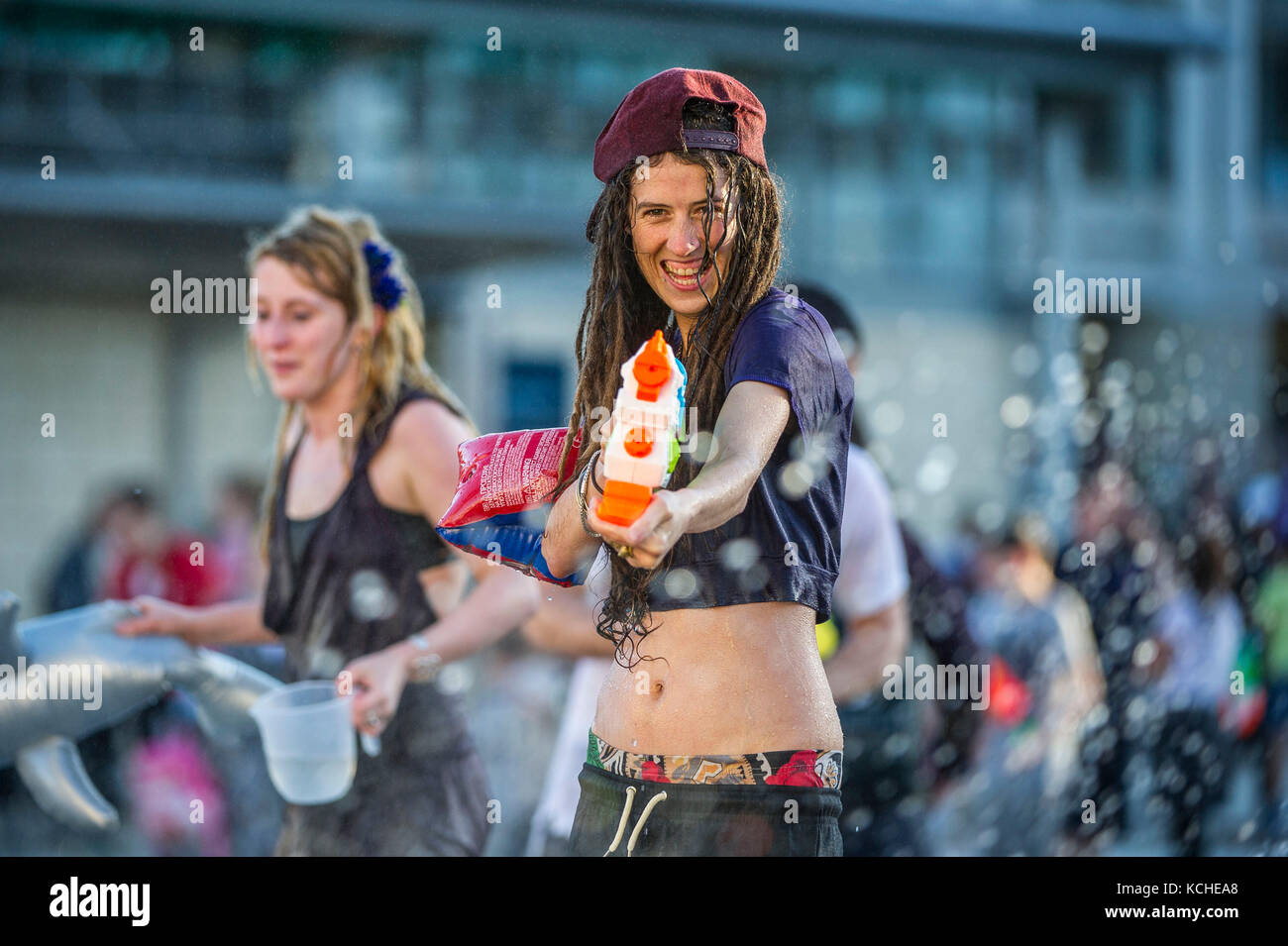 A woman with dreadlocks fires a water pistol during a charity water ...