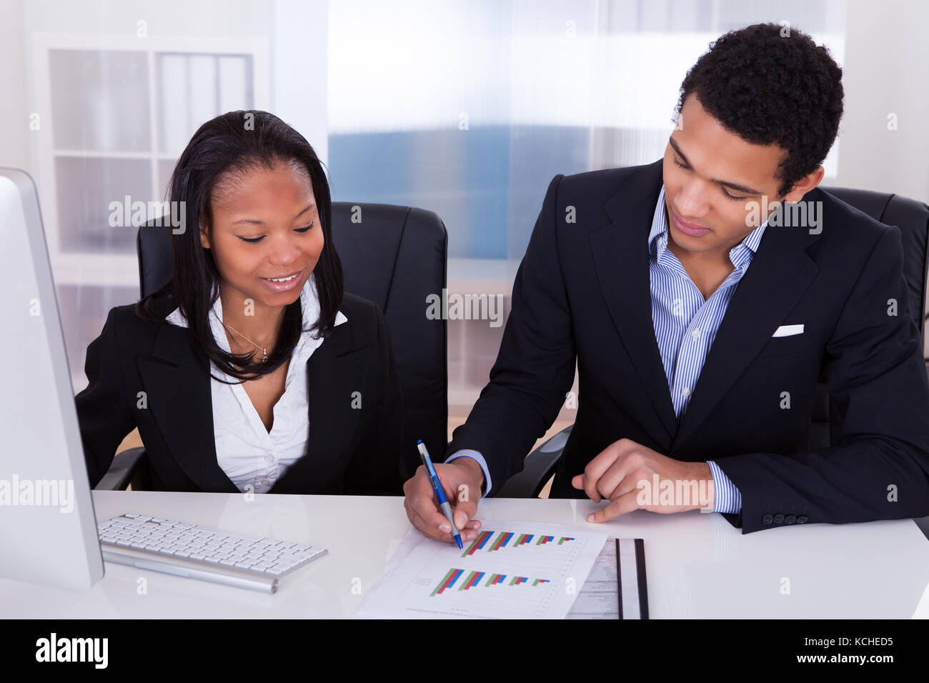 Portrait Of Happy Business People Sitting At The Desk Stock Photo - Alamy