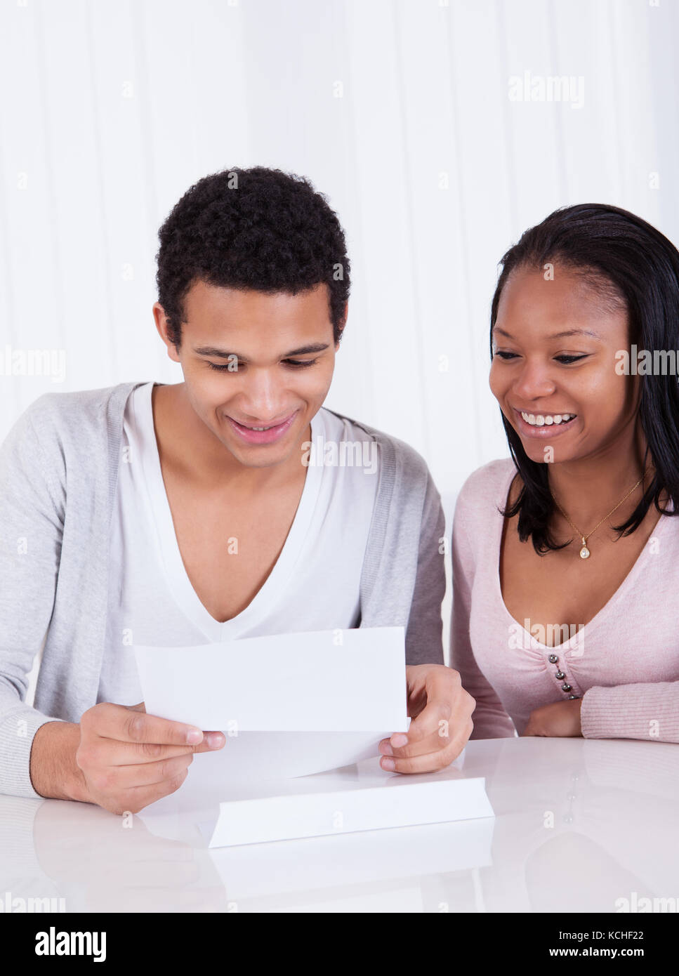 Portrait Of Happy Young Couple Looking At Paper Stock Photo - Alamy