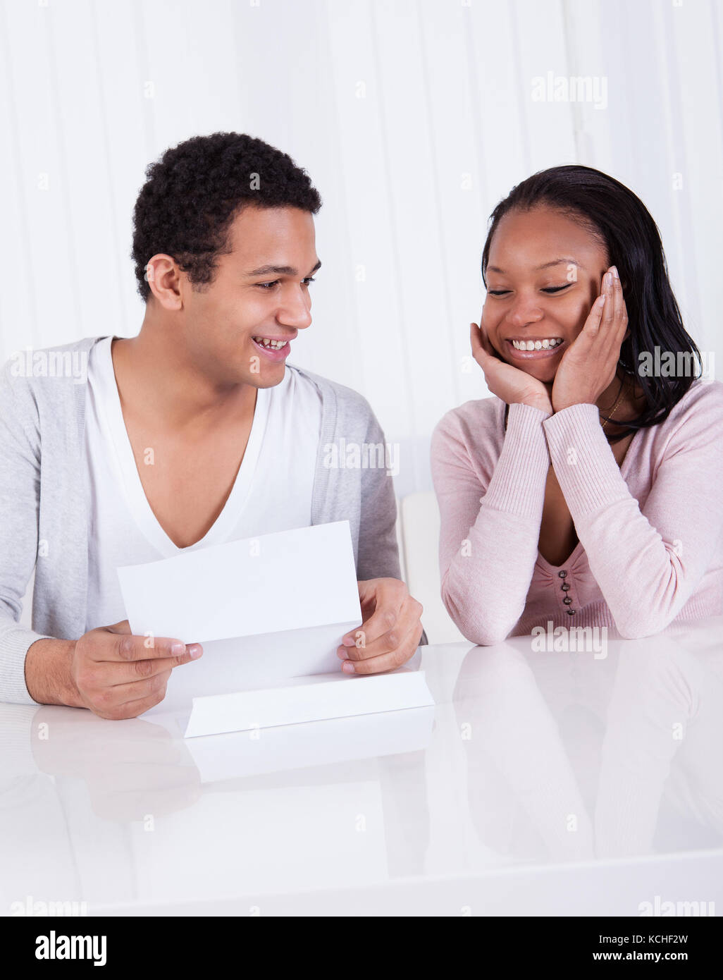 Portrait Of Happy Young Couple Looking At Paper Stock Photo - Alamy