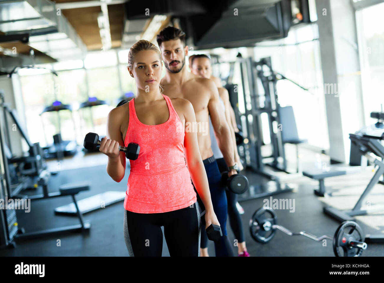 Personal trainer helping young woman with exercises for biceps Stock ...