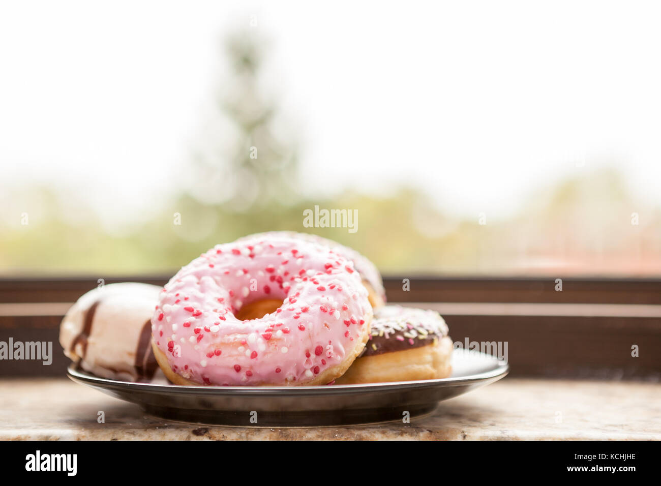 Plate with donuts next to window Stock Photo - Alamy