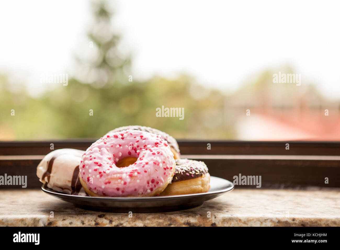 Plate with donuts next to window Stock Photo - Alamy