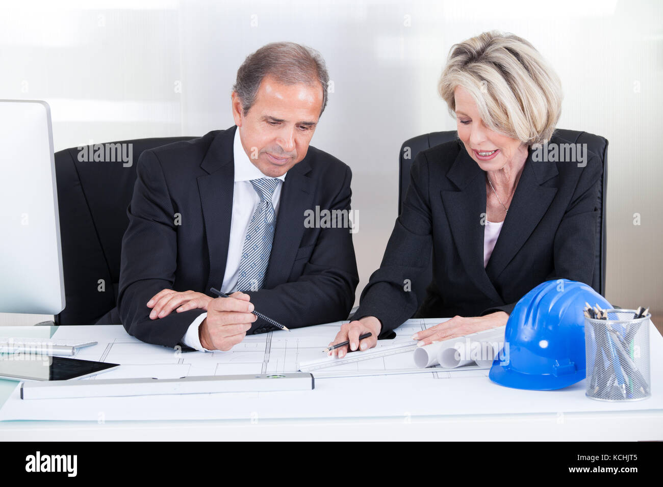Mature Engineers Looking At Plans Sitting At A Table Stock Photo - Alamy