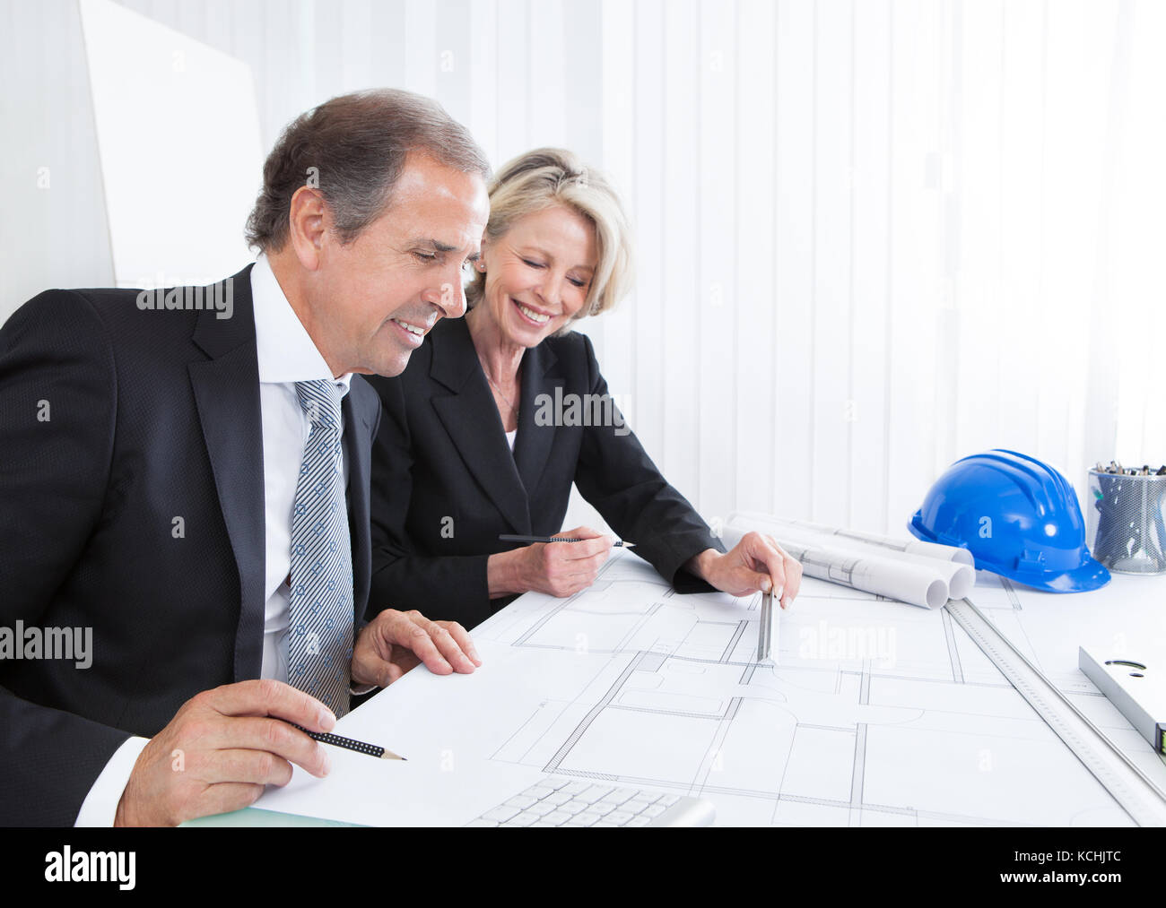 Mature Engineers Looking At Plans Sitting At A Table Stock Photo - Alamy