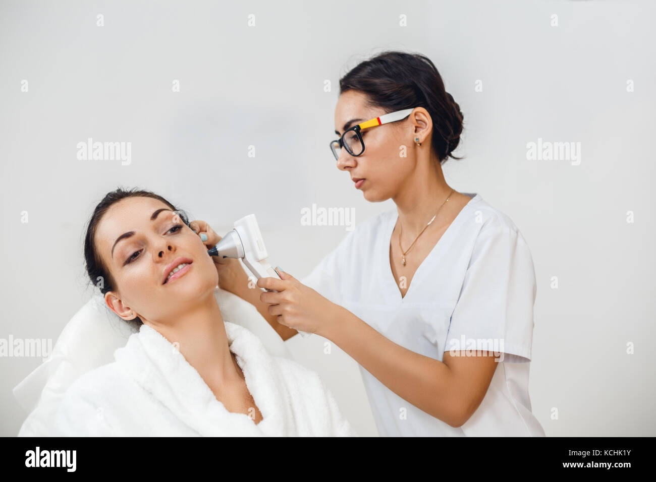 Young female doctor examining patient's ear in clinic Stock Photo - Alamy
