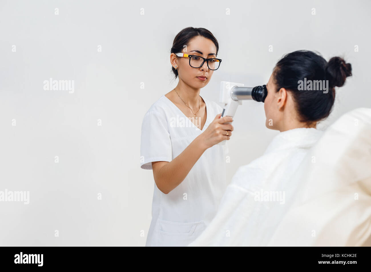 Female optometrist with special equipment checking patient vision at ...