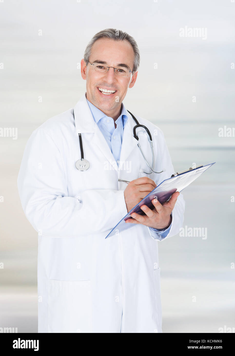 Portrait of a happy doctor writing on clipboard Stock Photo - Alamy