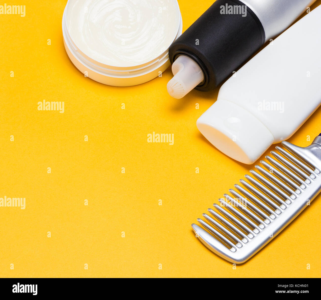 Various hair styling products with a comb on bright yellow background ...