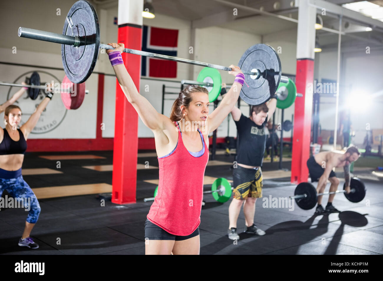 Full length of determined female lifting heavy barbell in gym Stock ...