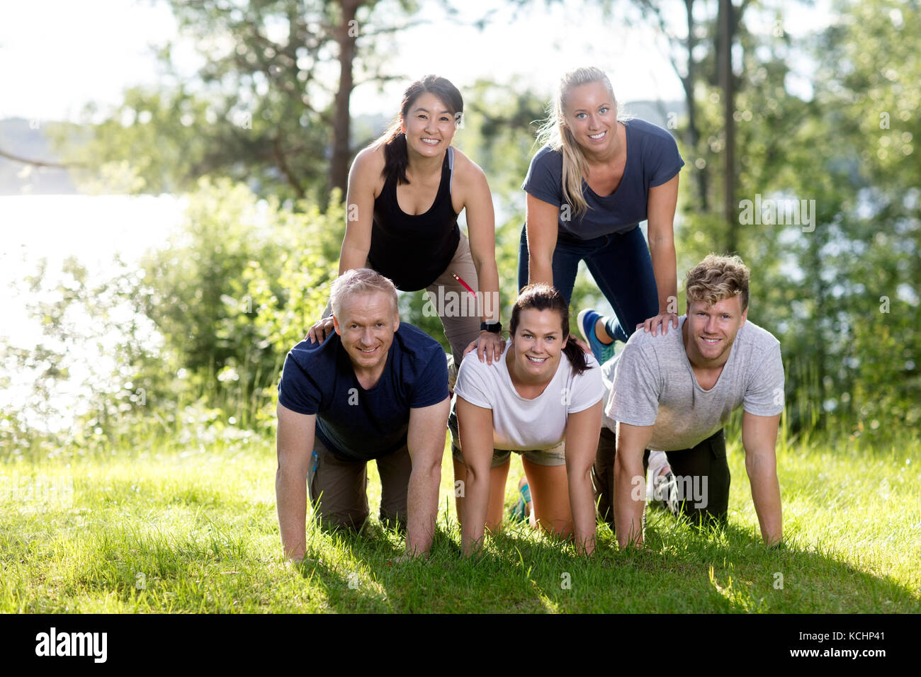 Portrait of happy male and female friends making human pyramid on ...