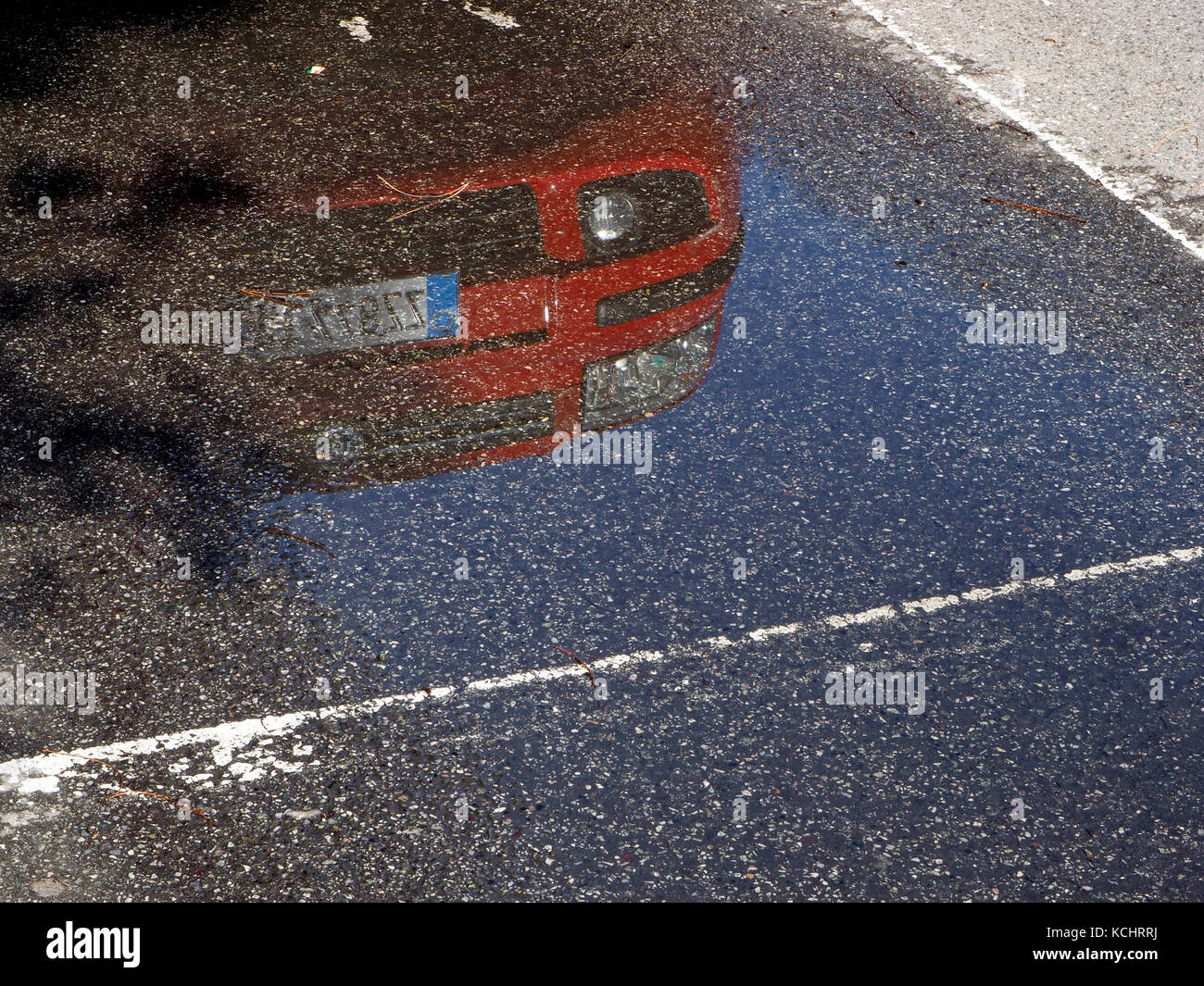 reflection of red car in parking bay puddle in Tuscany, Italy Stock ...