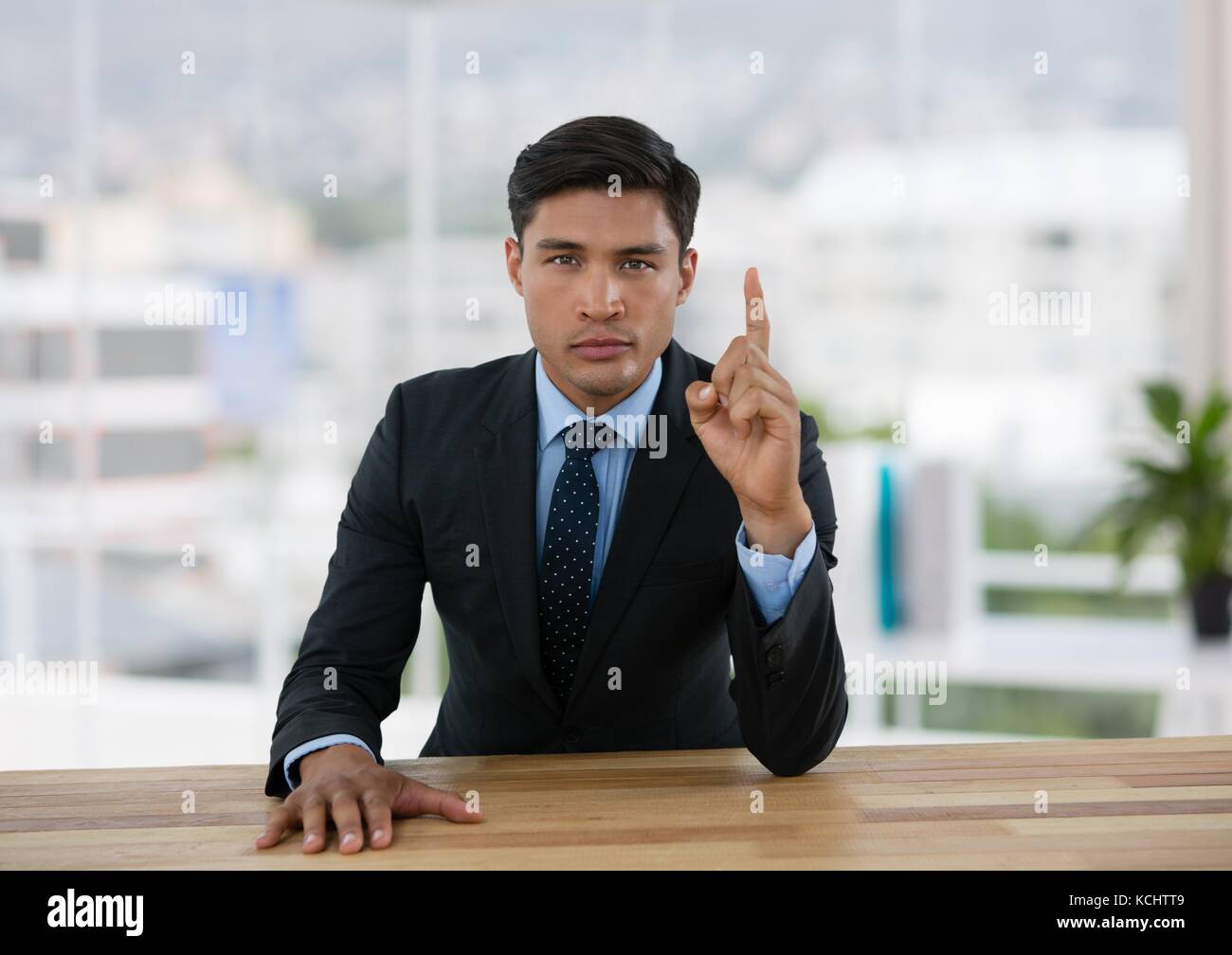 Digital composite of Business man pointing up while sits at his desk in ...