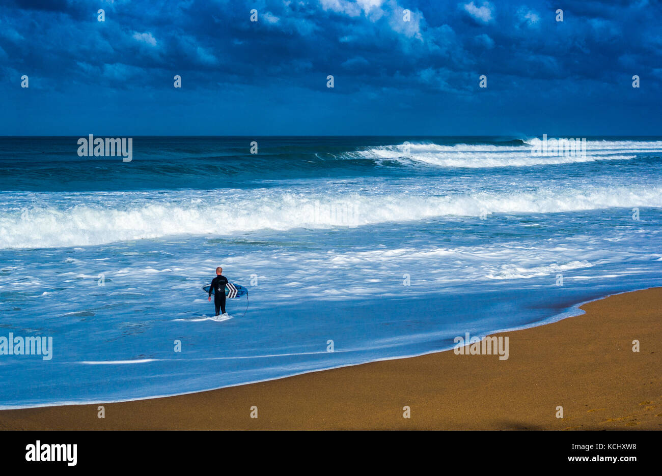Lone surfer standing alone about to paddle into the surf Stock Photo ...