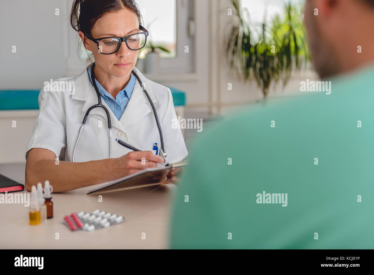 Doctor writing a prescription to patient Stock Photo - Alamy