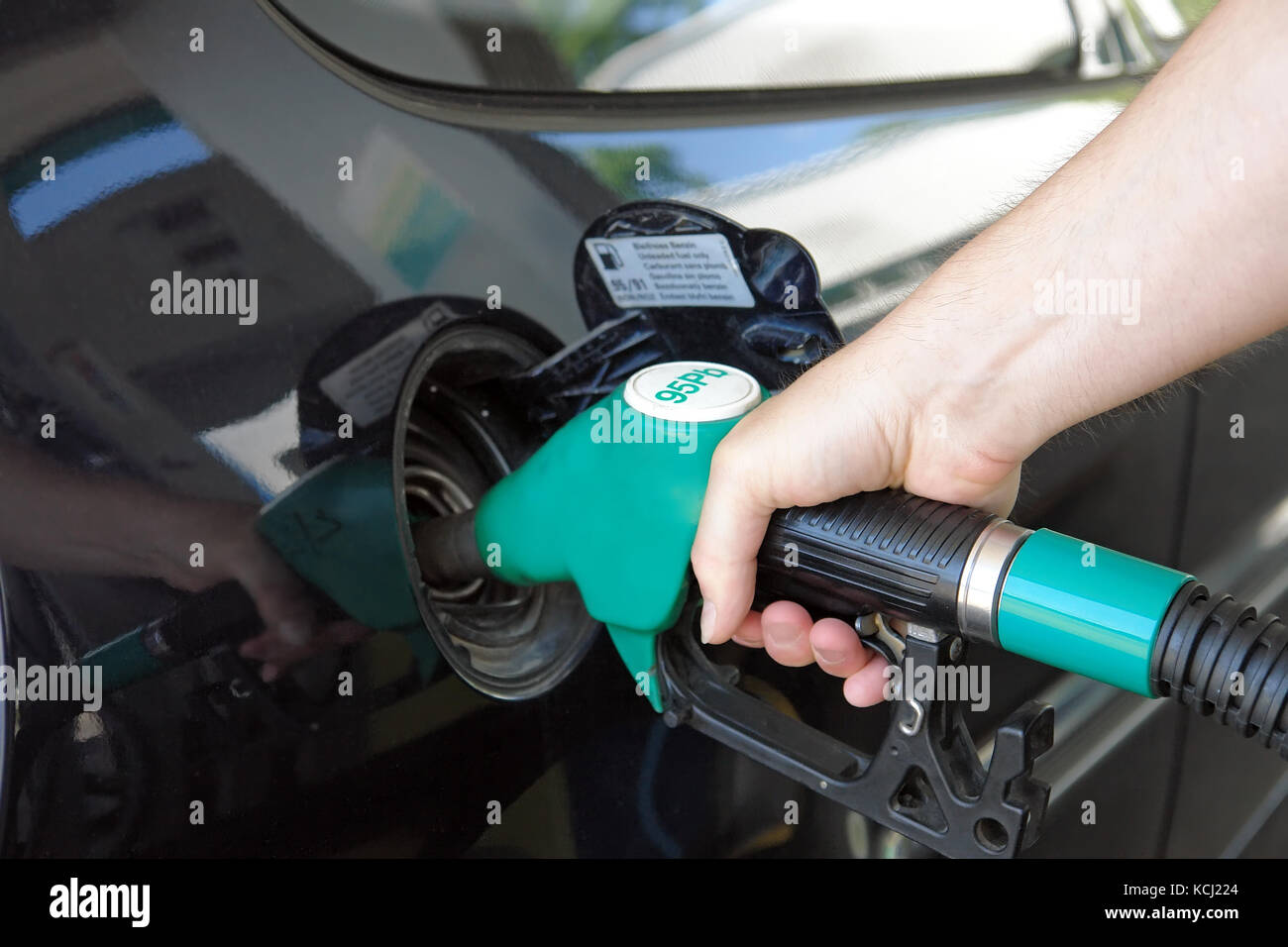 Closeup of male hand topping up car tank with unleaded 95 gasoline ...