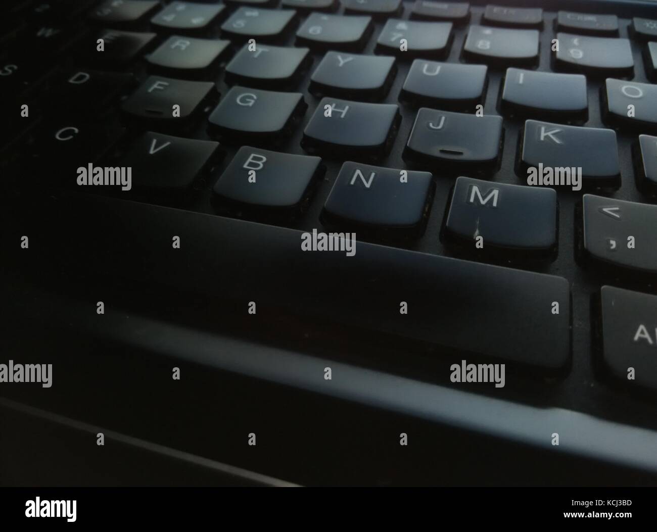 Close-up of laptop keyboard illuminated by the laptop's own screen ...