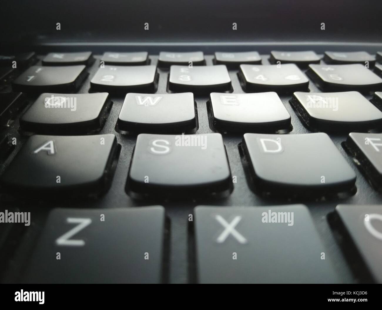 Close-up of laptop keyboard illuminated by the laptop's own screen ...