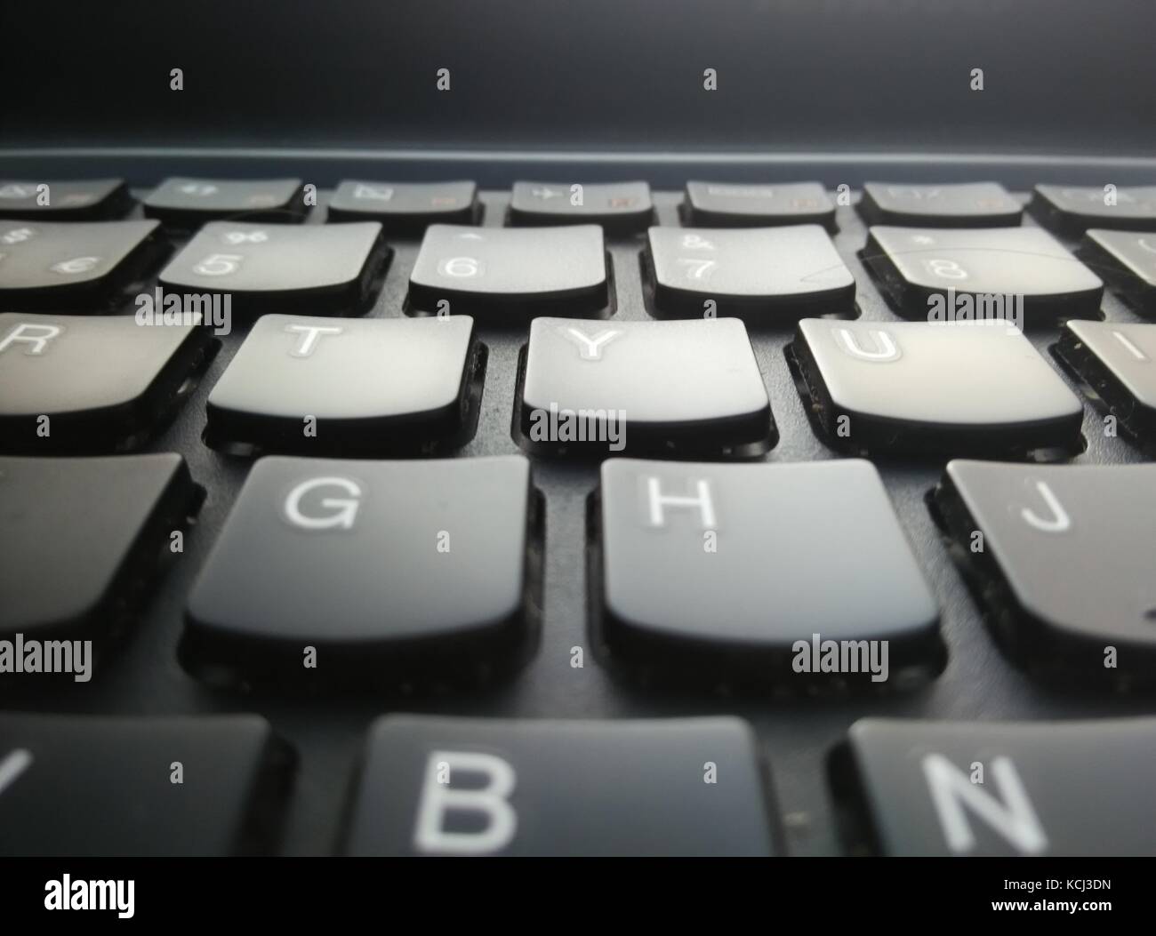 Close-up of laptop keyboard illuminated by the laptop's own screen ...