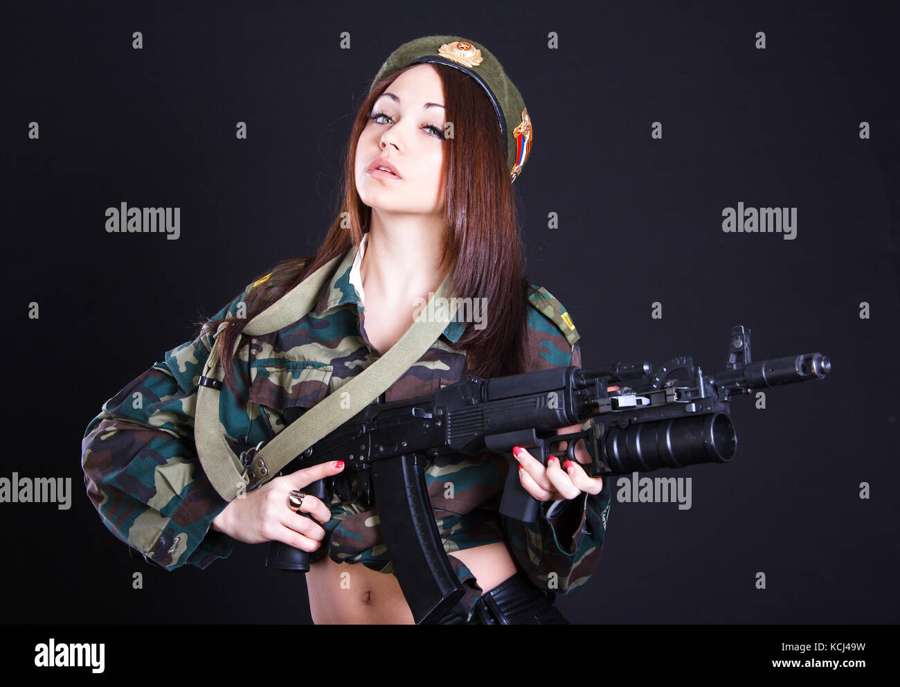 Young woman in the military uniform with the assault rifle over black ...
