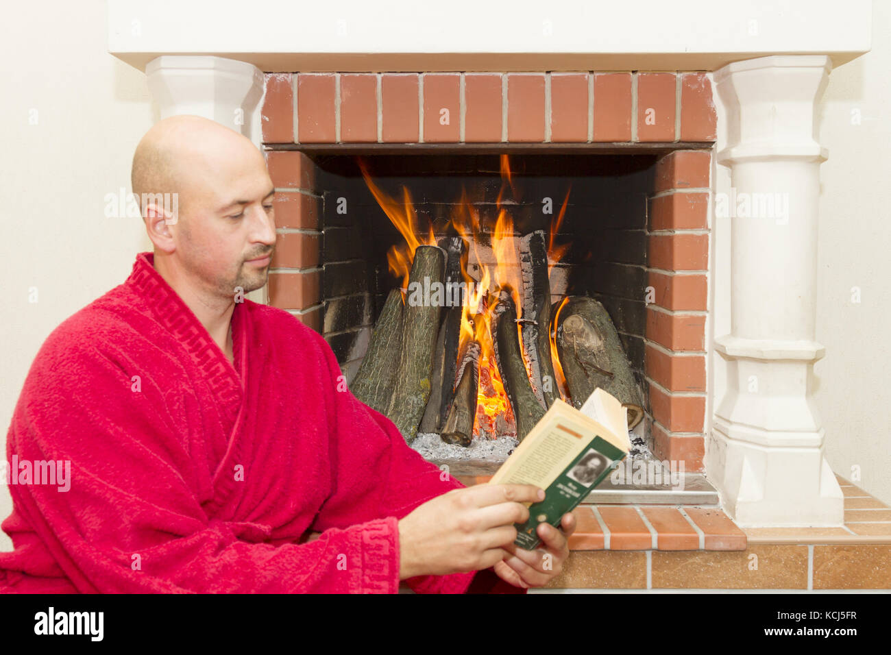 young man reading a book near the fireplace Stock Photo - Alamy
