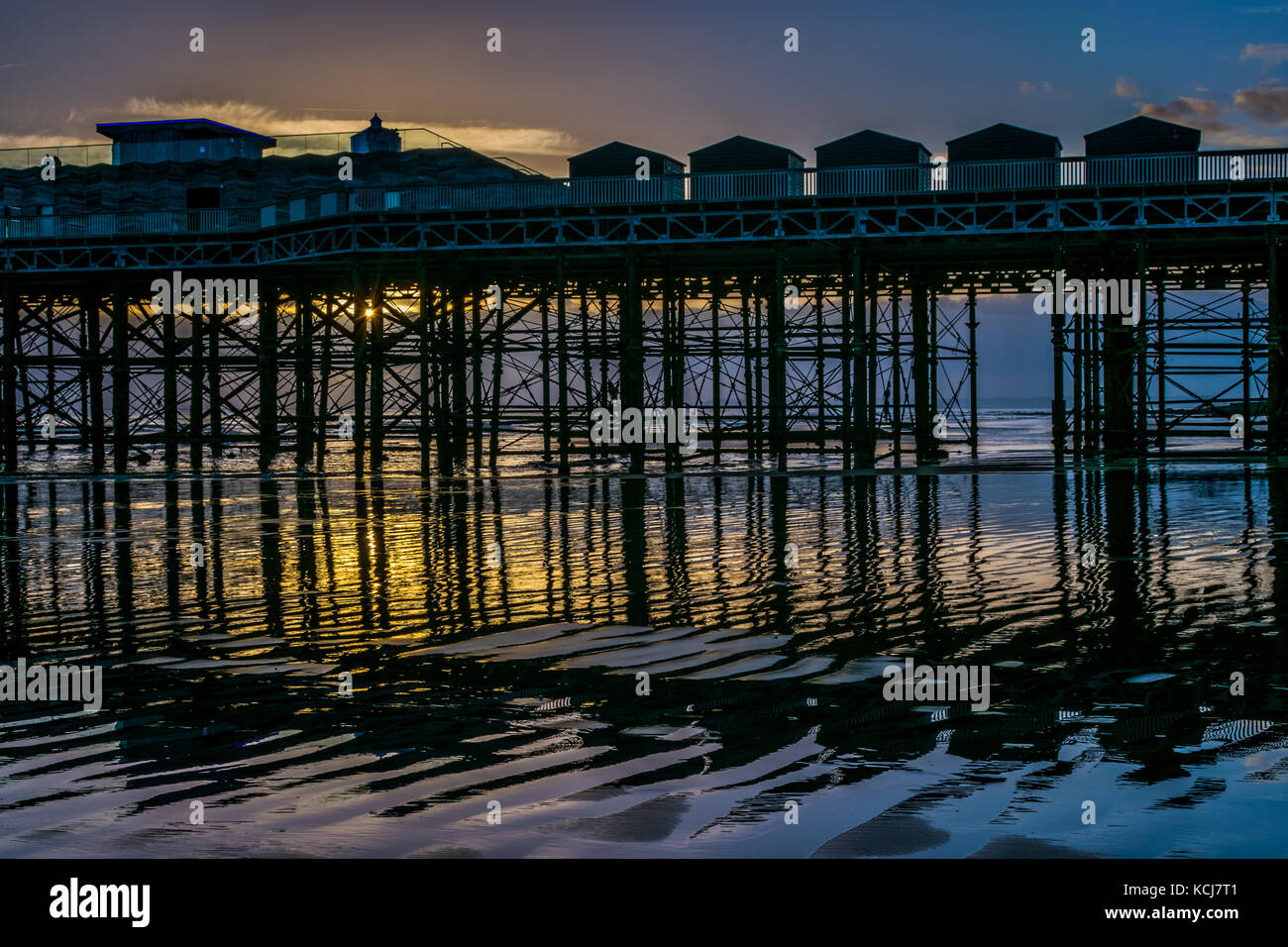 Hastings pier iron structure reflected in wet sand at sunset and at low ...