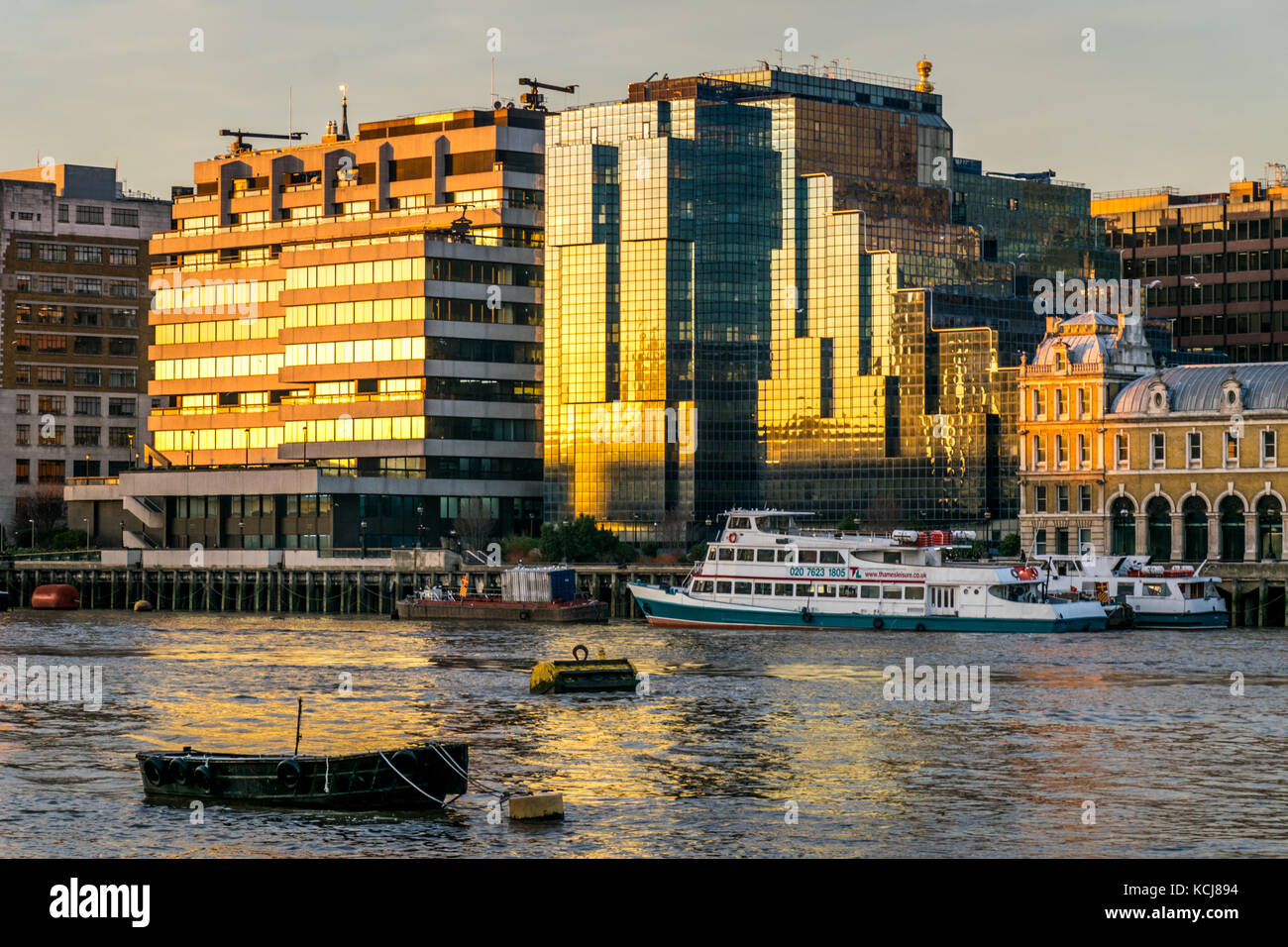 Golden sunset reflecting off modern new buildings on bank of River ...