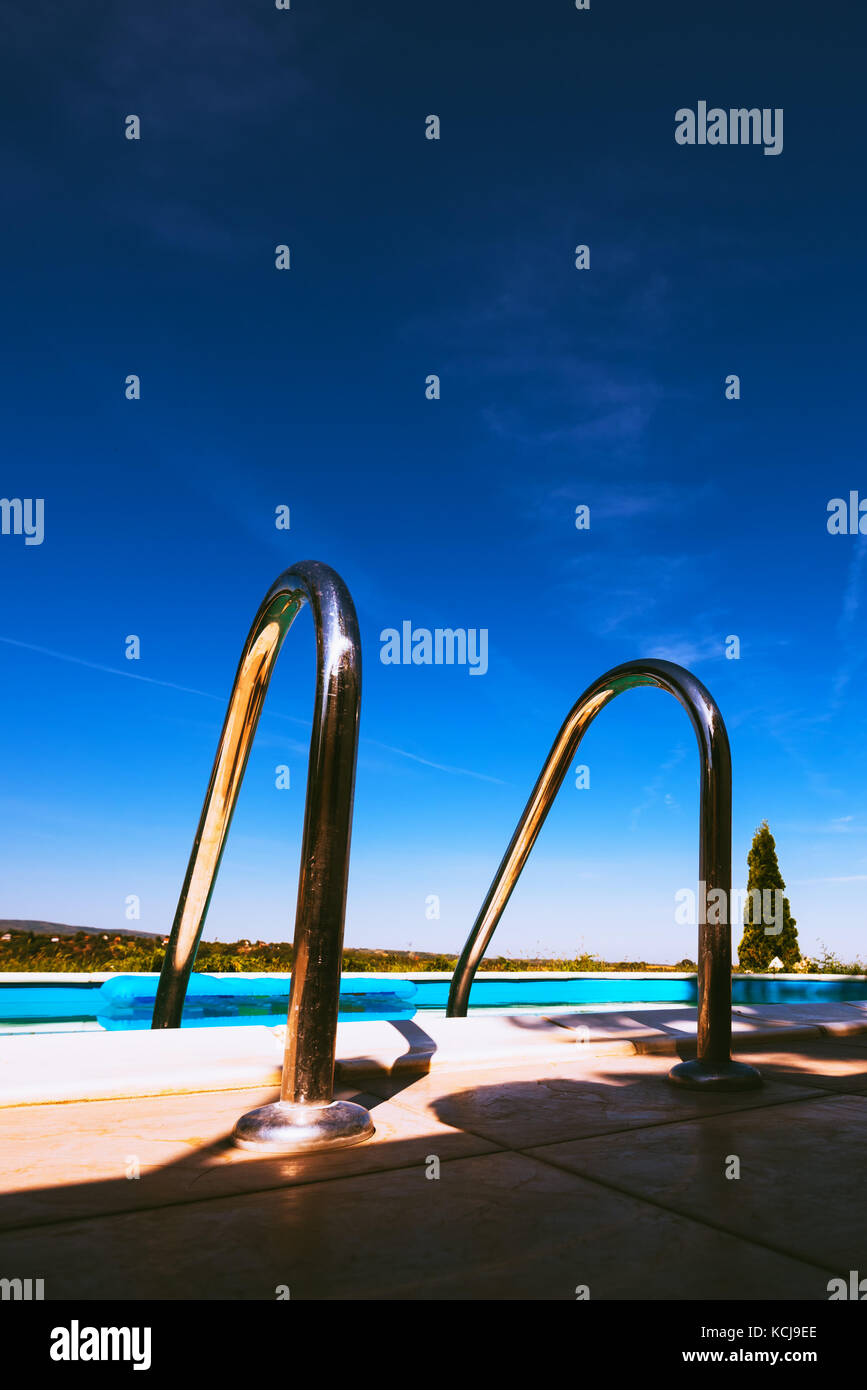Swimming pool ladders, private outdoor poolside on sunny summer ...