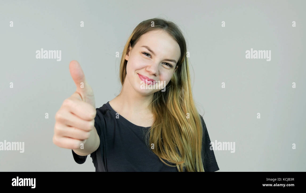 Happy smiling beautiful young woman showing thumbs up gesture on white ...