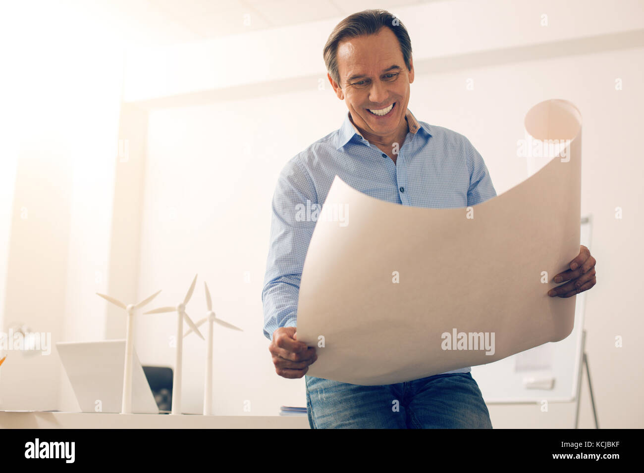 Cheerful positive engineer looking at the blueprint Stock Photo - Alamy