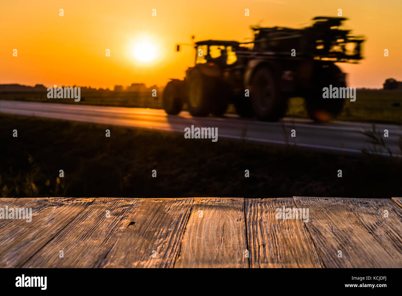 Empty rustic wood table top with tractor silhuette at sunset background ...