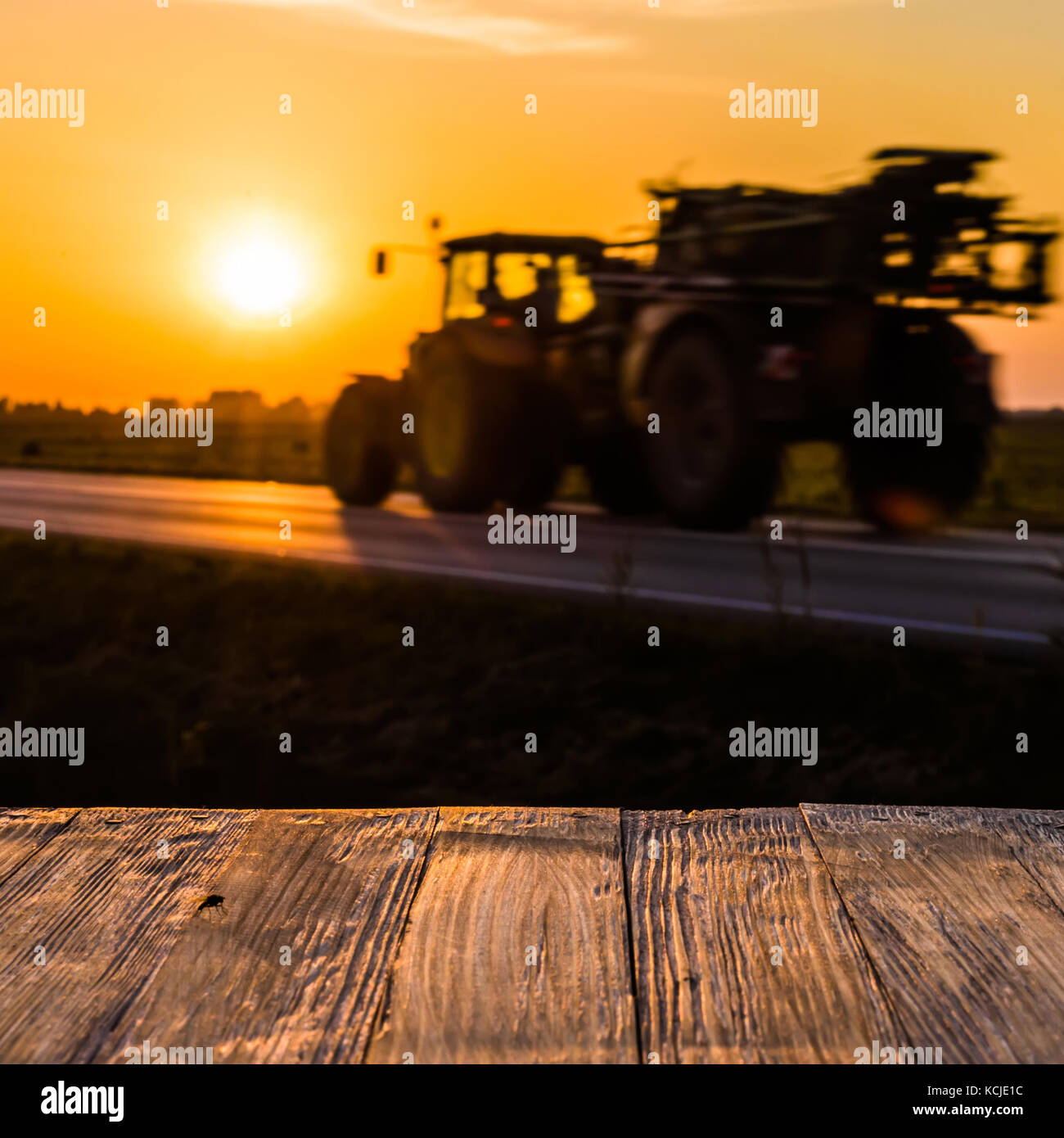 Empty rustic wood table top with tractor silhuette at sunset background ...