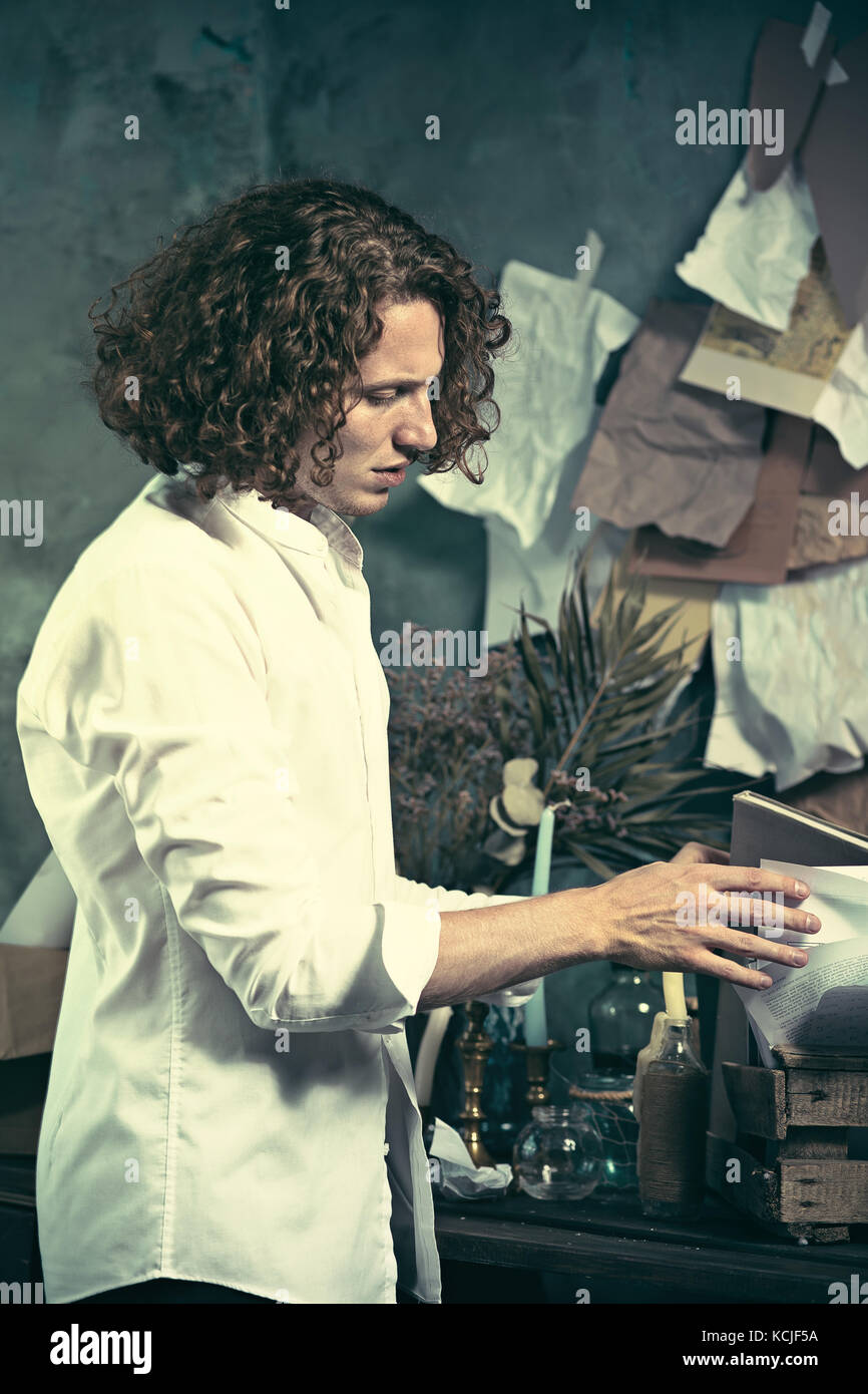 Writer at work. Handsome young writer standing near the table and ...